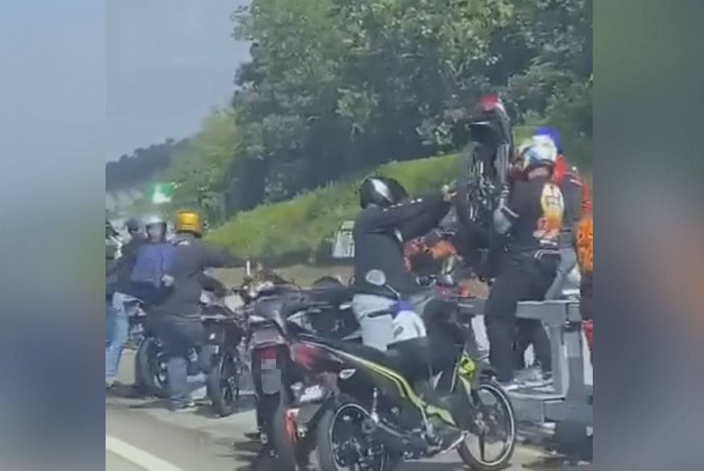 Riders carry motorcycles to cross divider to avoid roadblock - Sinar Daily